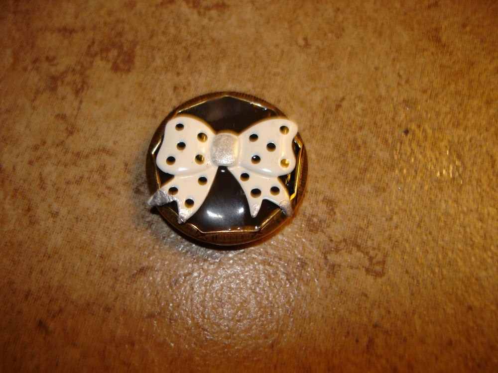 Large gold metal button with large bow.