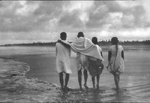 Mahatma Gandhi walking on a beach with some youngsters. - 8x10 photo